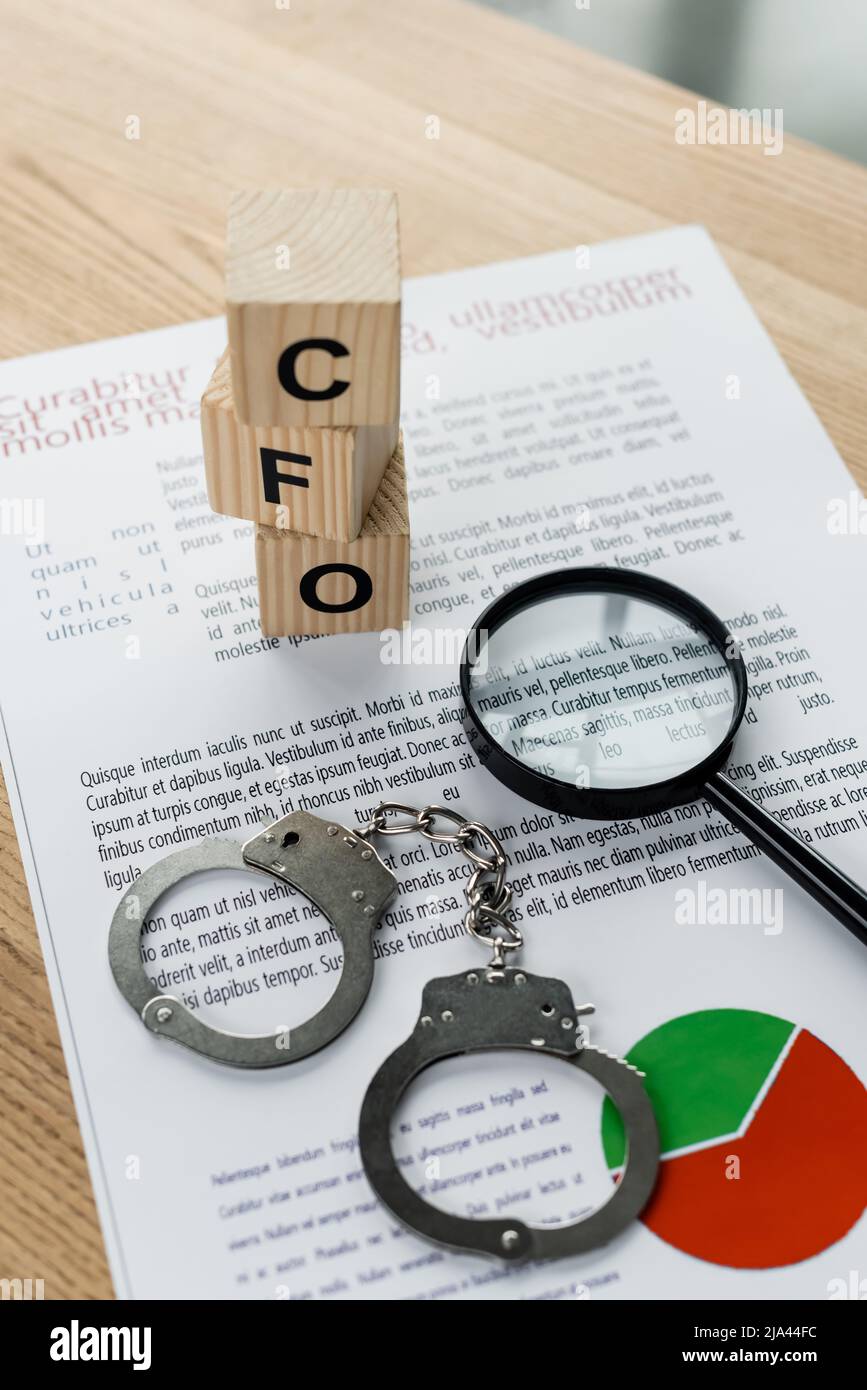 magnifying glass near cubes with cfo letters, charts and handcuffs on ...
