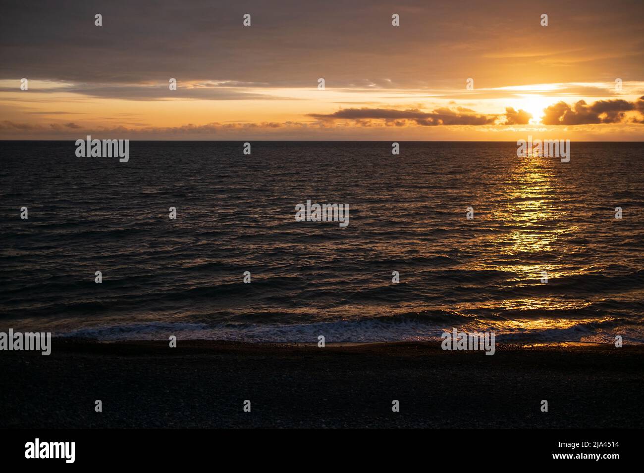 Calm sea with sunset sky and sun through the clouds over. Ocean and sky ...