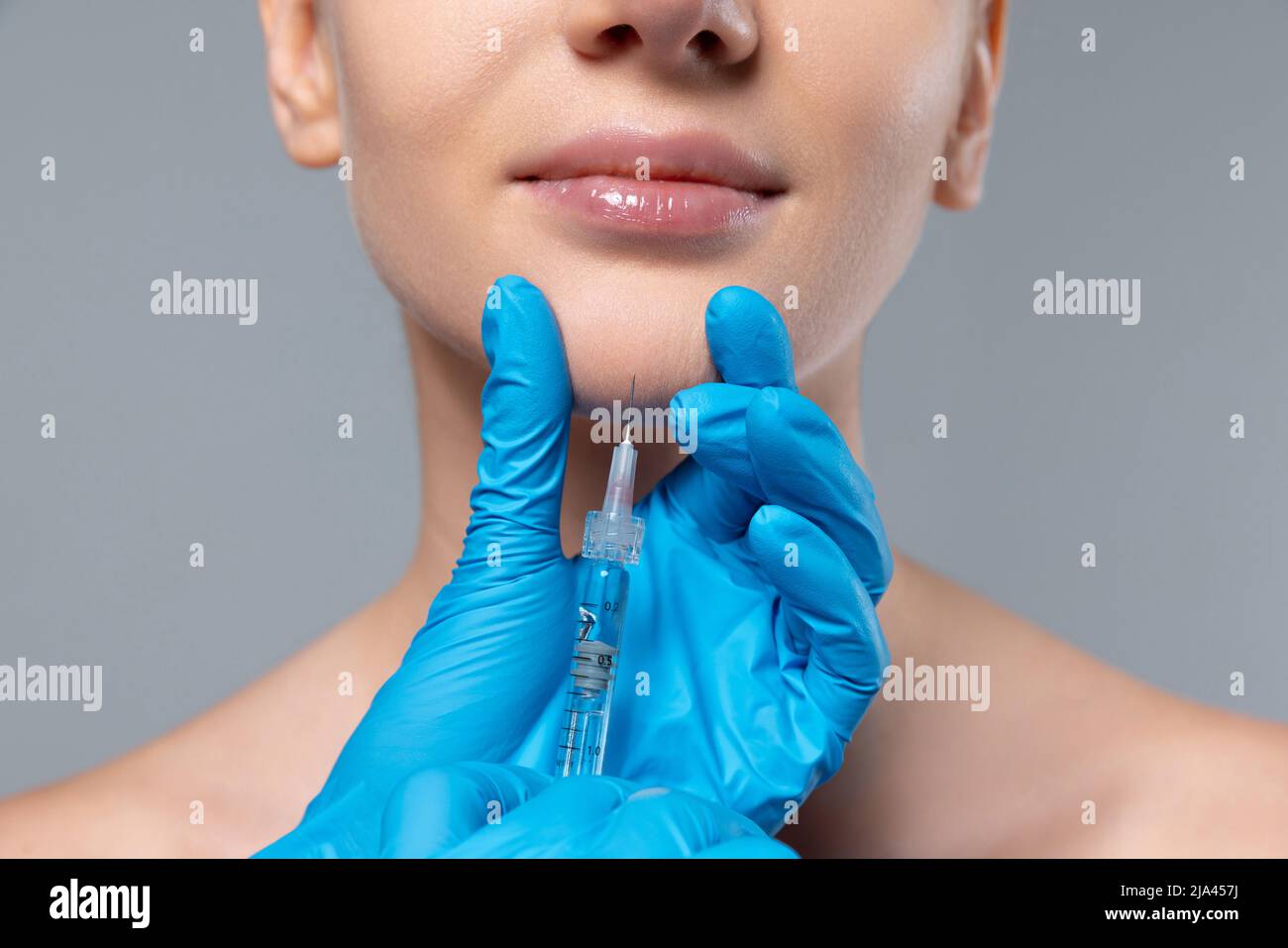 Portrait of young girl doing cosmetology injections isolated over grey ...