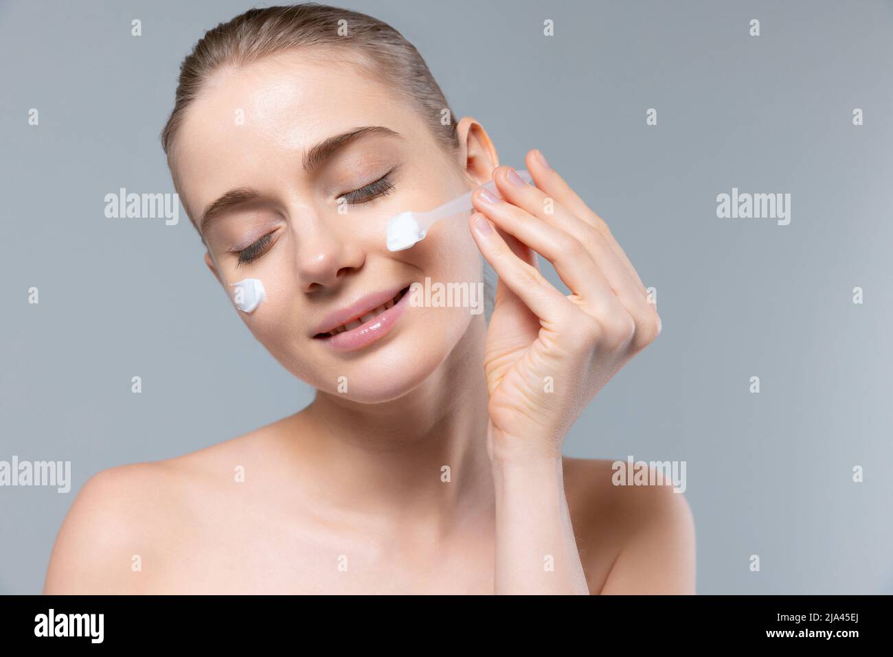 Portrait of tender beautiful woman taking care after skin, applying ...