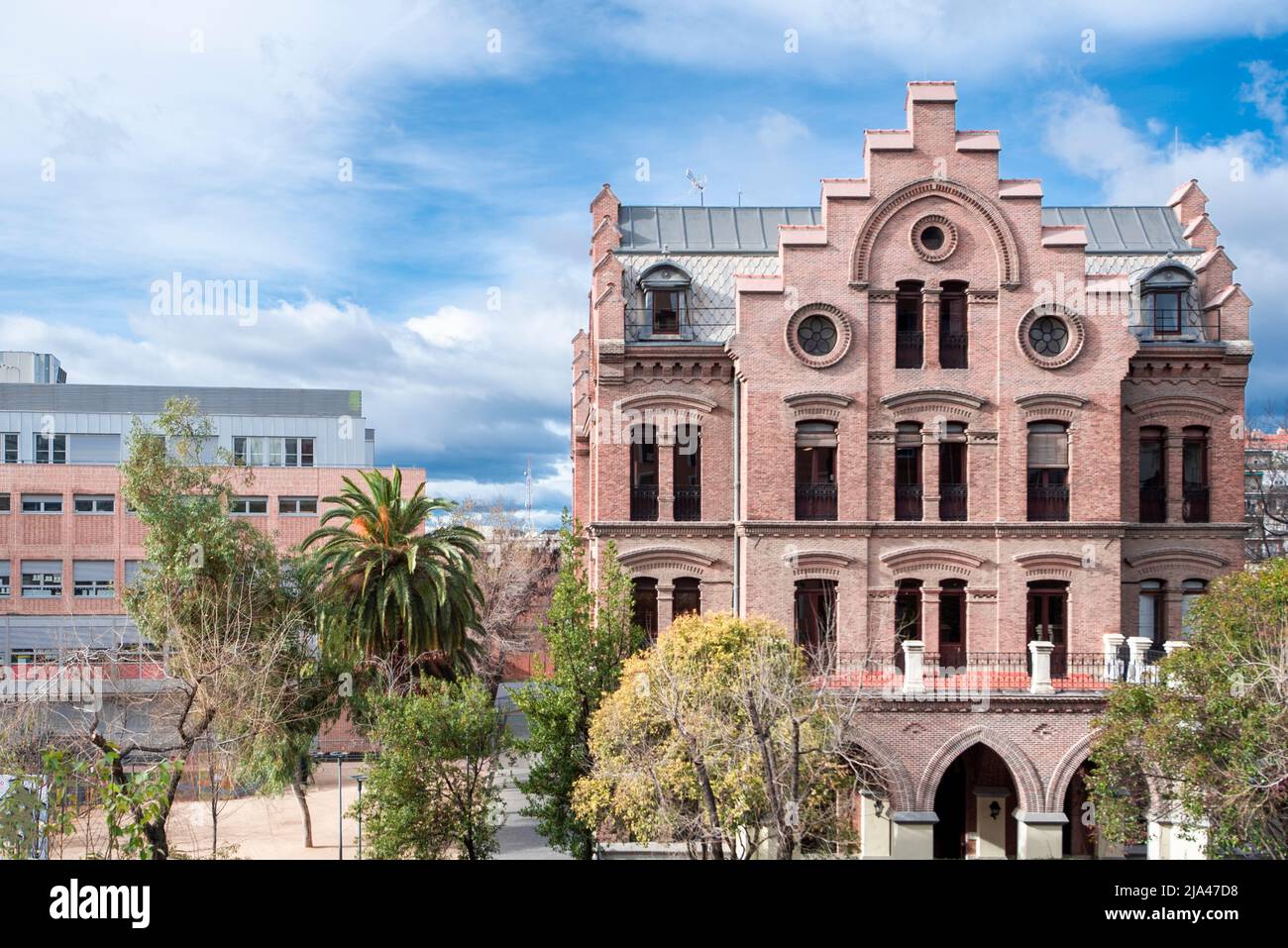 Facades of a vintage monumental building surrounded by trees and palm ...