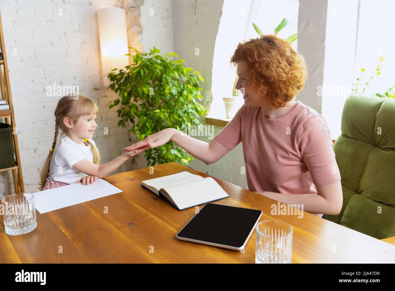 Activities with tutor. Young woman and cute little girl, mother and ...