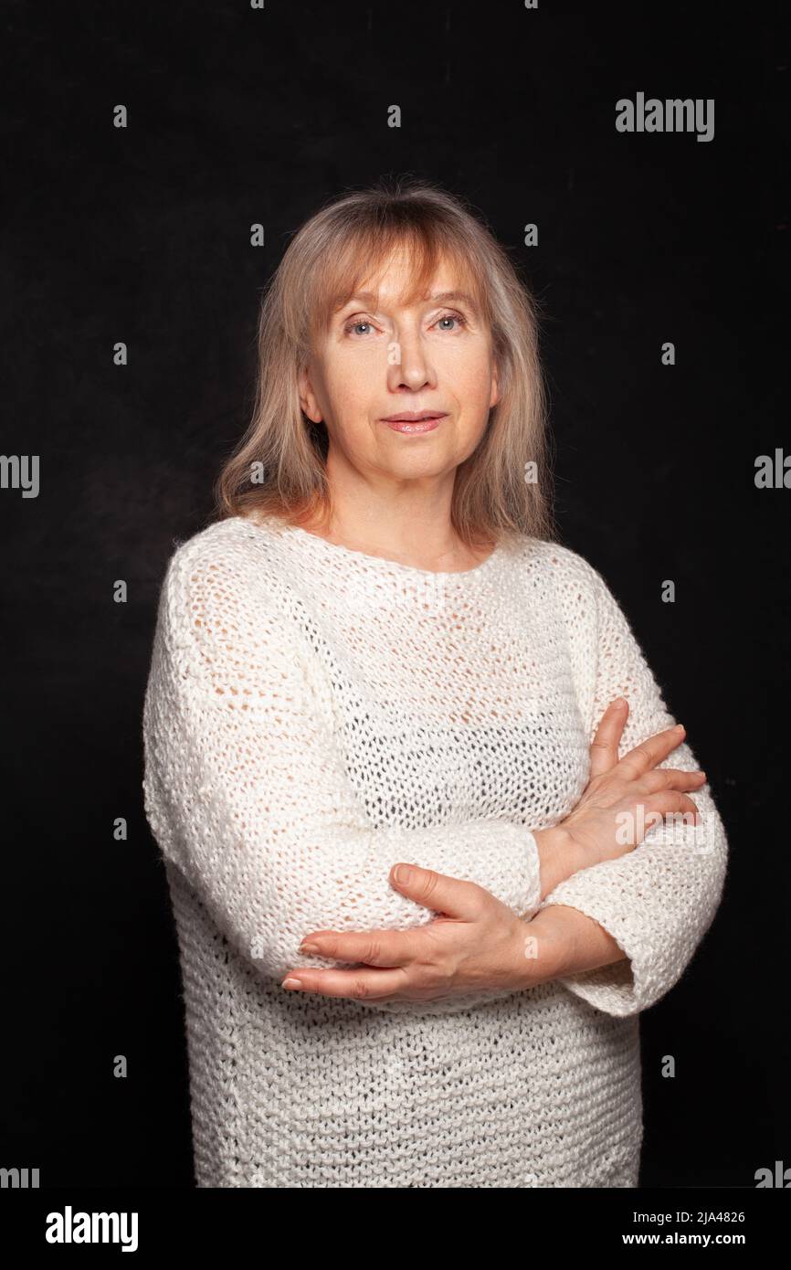 Portrait of senior woman wearing white sweater posing on black ...