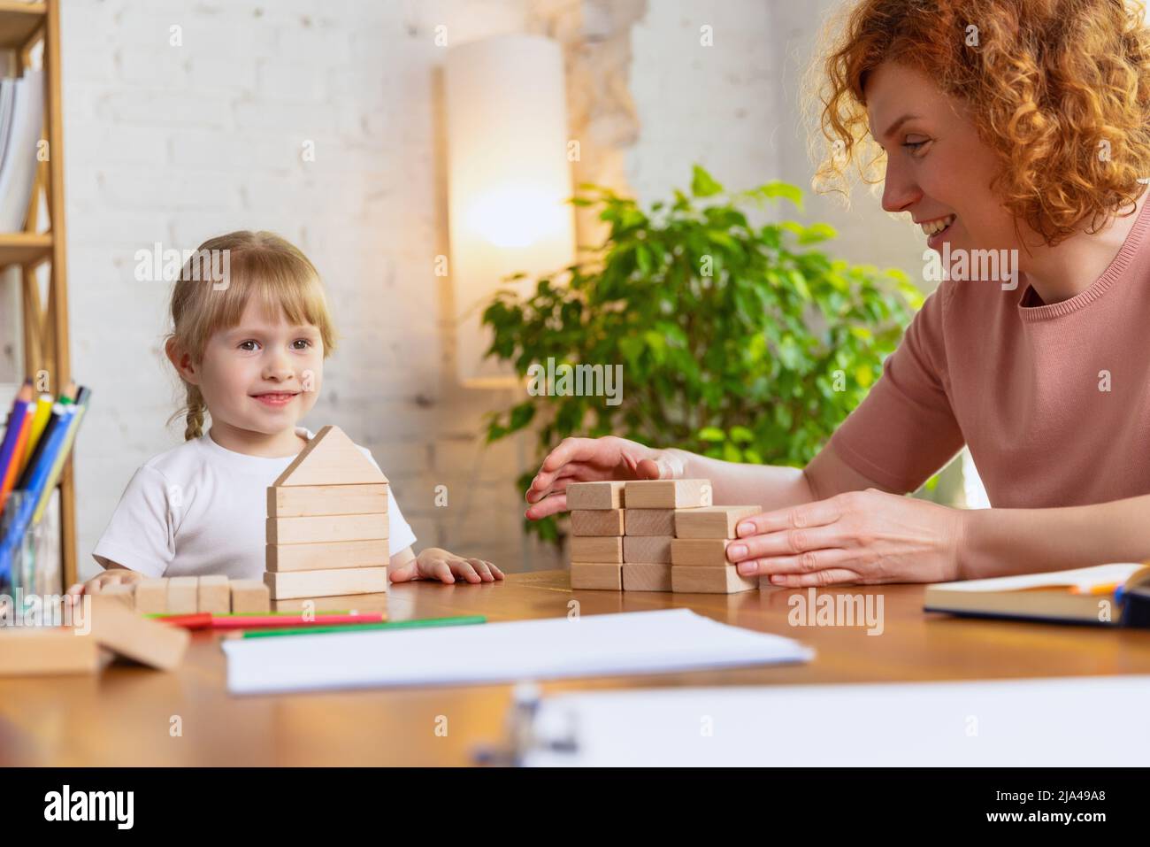 Activities with tutor. Young woman and cute little girl, mother and ...