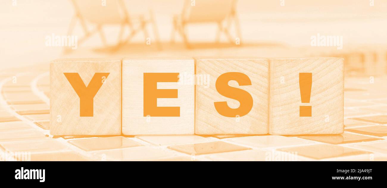 The word Yes written in black letters on wooden blocks in ocean ...