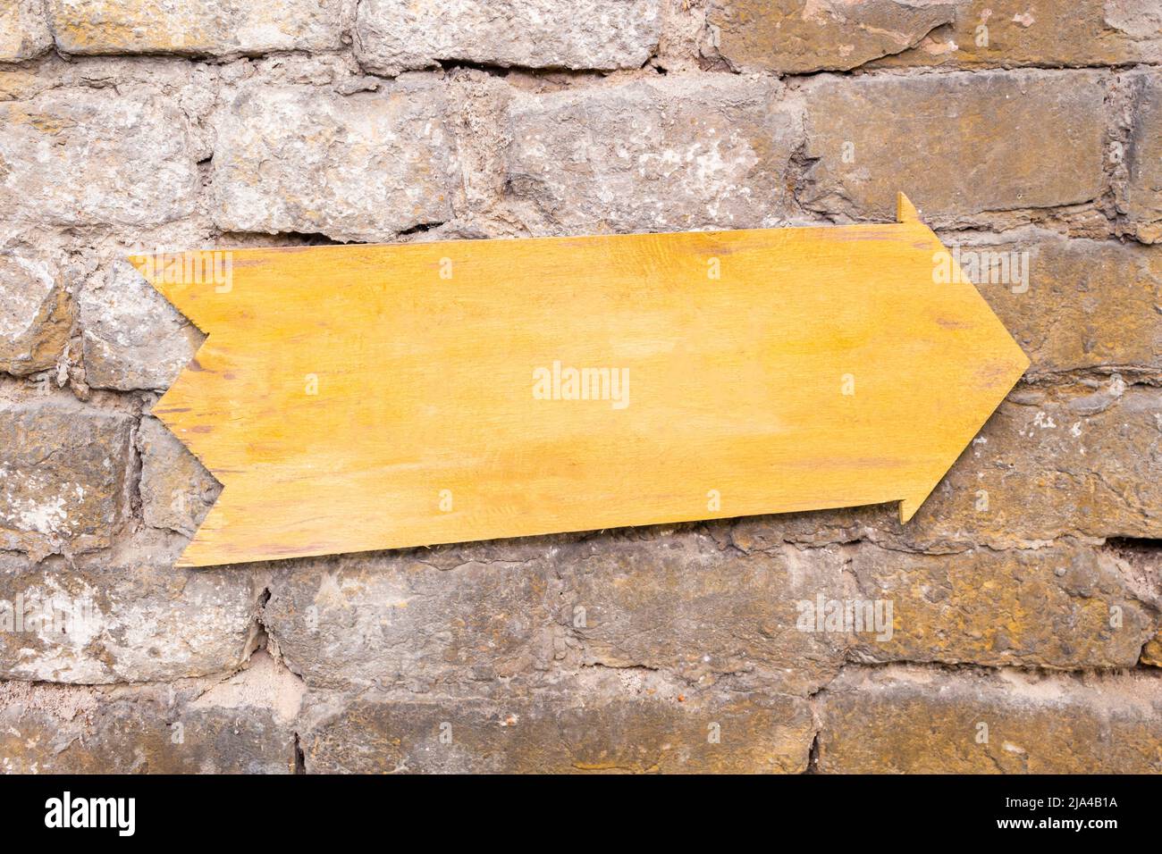 Arrow wooden sign hanging on a rustic brick wall. Emty space, add text ...