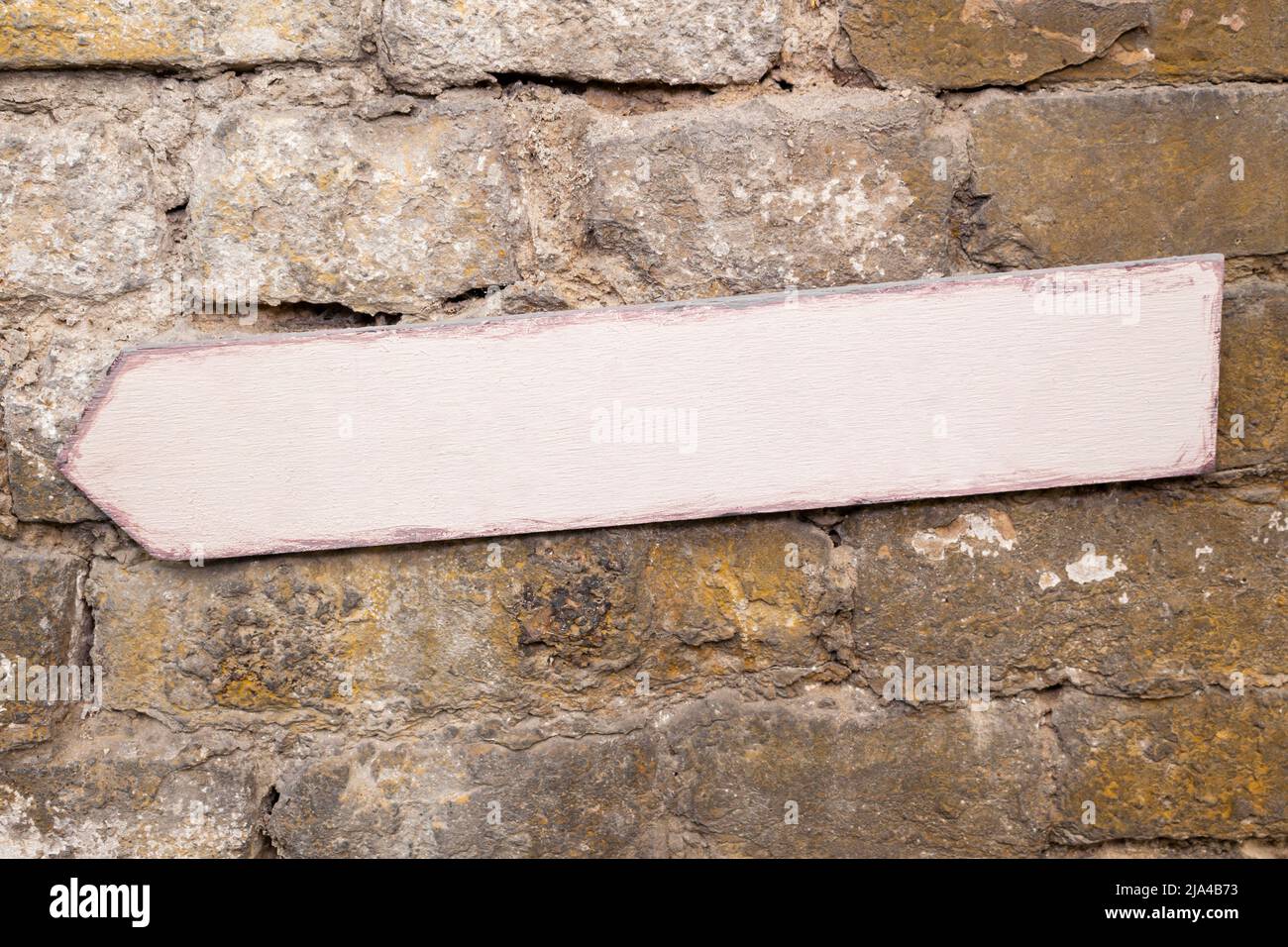 Arrow wooden sign hanging on a rustic brick wall. Emty space, add text ...