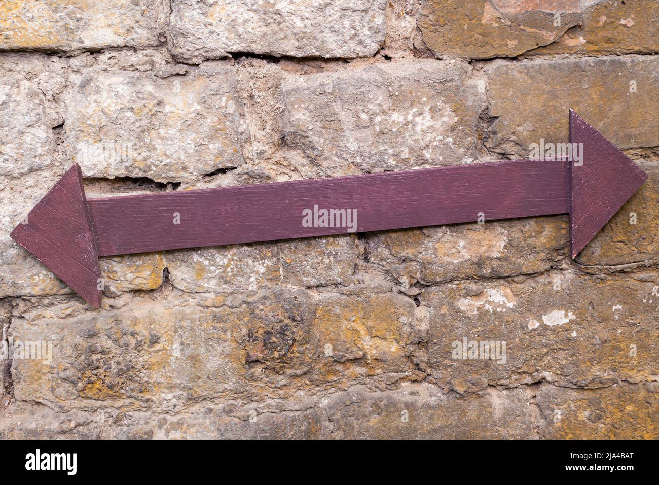 Arrow wooden sign hanging on a rustic brick wall. Emty space, add text ...