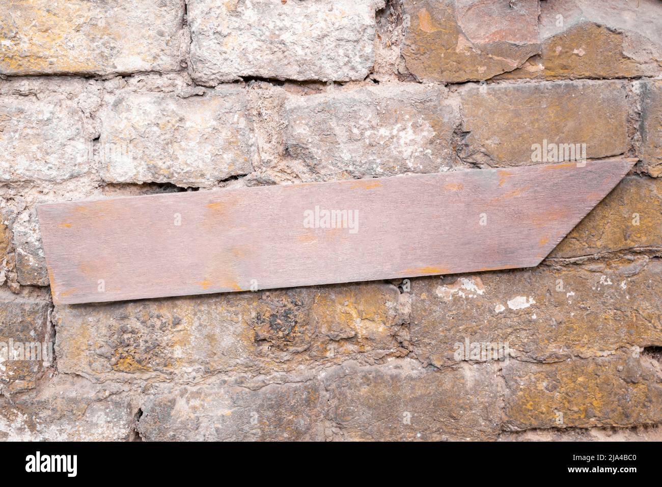 Arrow wooden sign hanging on a rustic brick wall. Emty space, add text ...