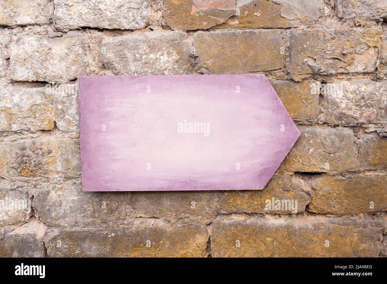 Arrow wooden sign hanging on a rustic brick wall. Emty space, add text ...