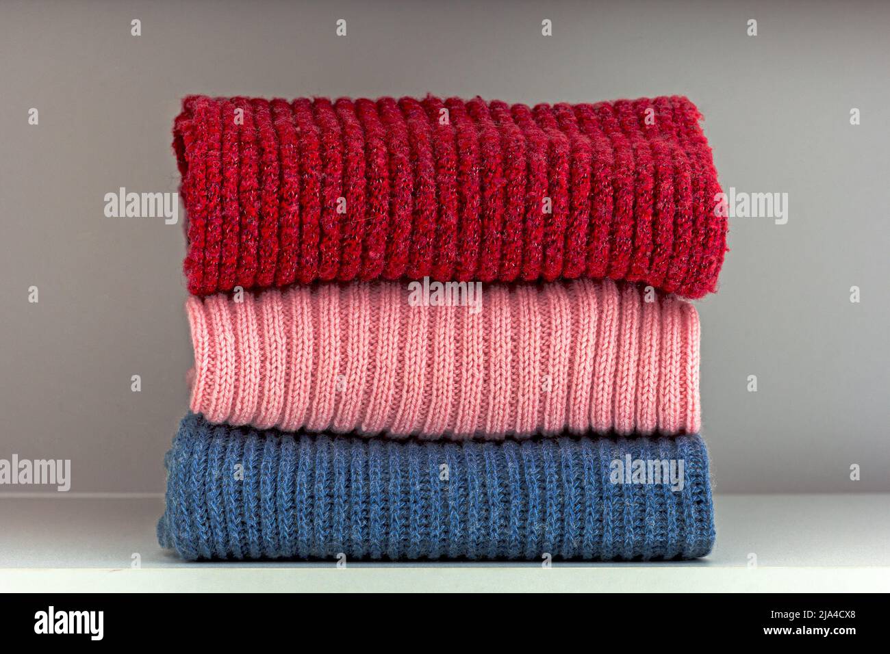 Stack of red, pink and blue wool cloth on shelf in white wardrobe Stock ...