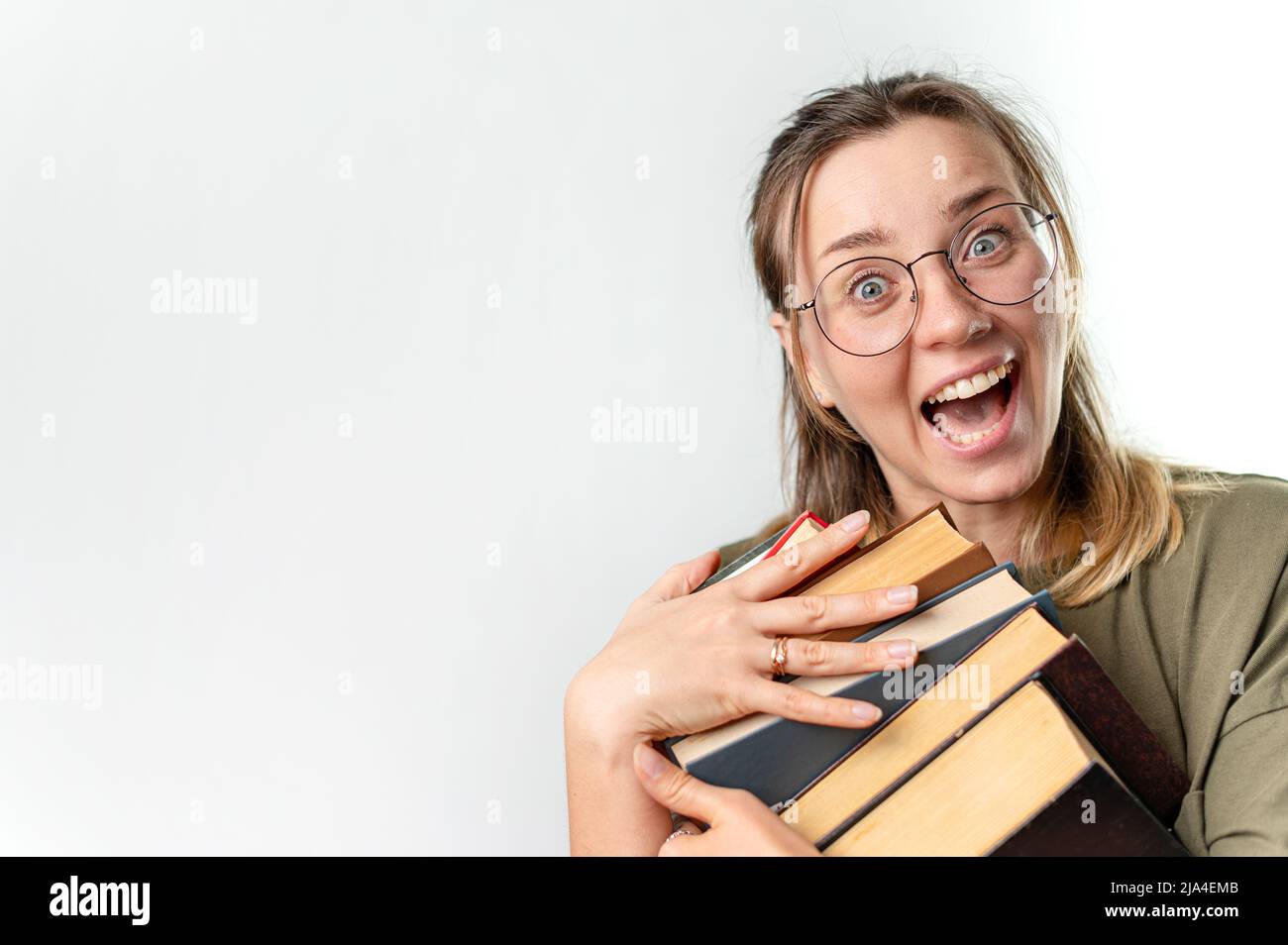 Young excited happy woman student holding books by her face on white ...