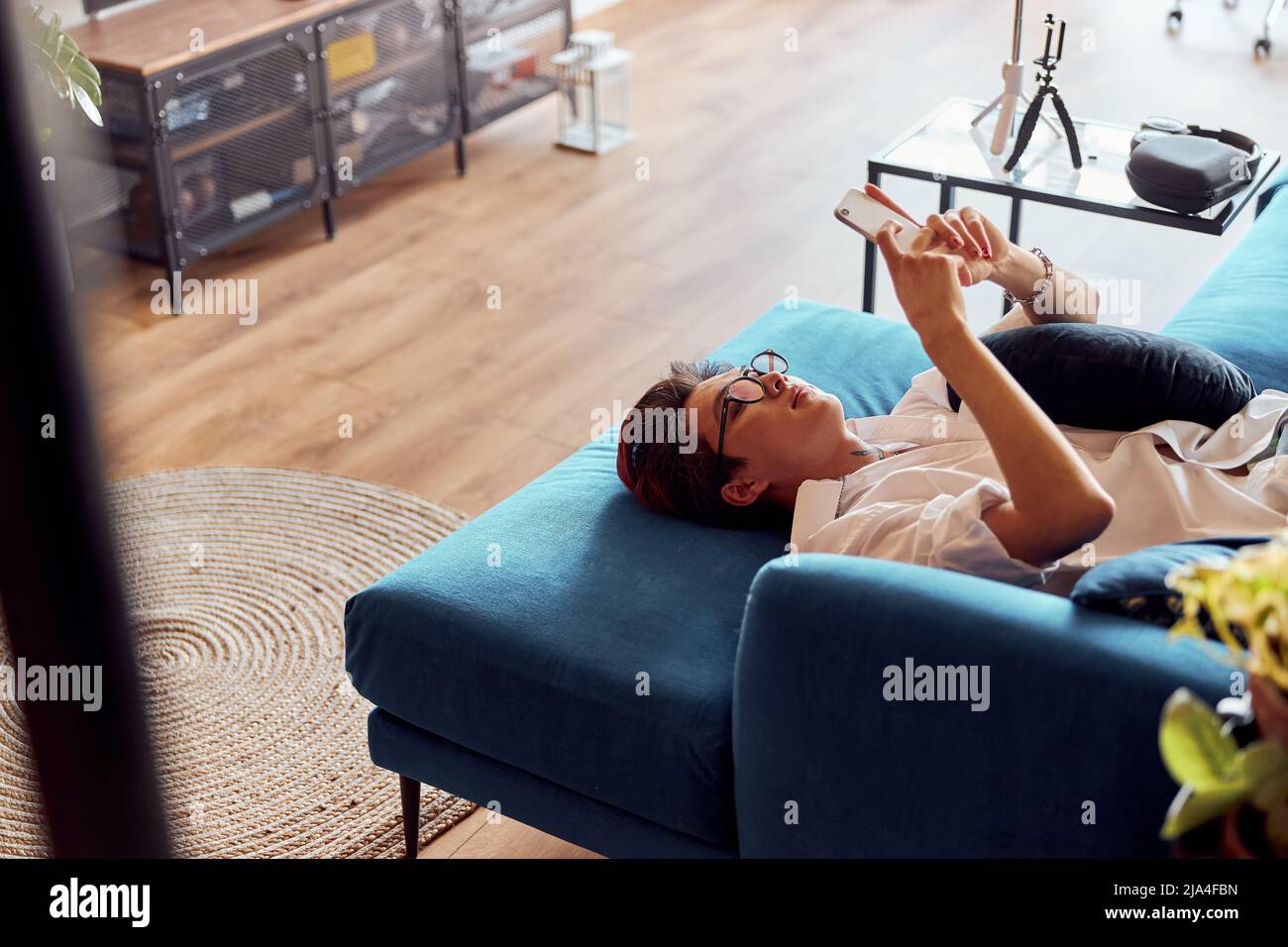 Relaxed Asian guy using a smart phone lying on an couch Stock Photo - Alamy