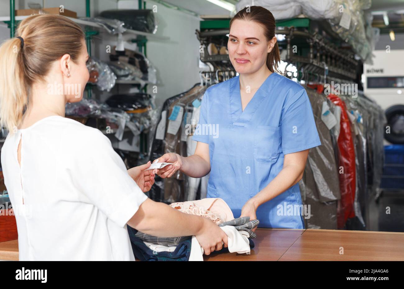 Woman receiving clothing for dry cleaning Stock Photo - Alamy