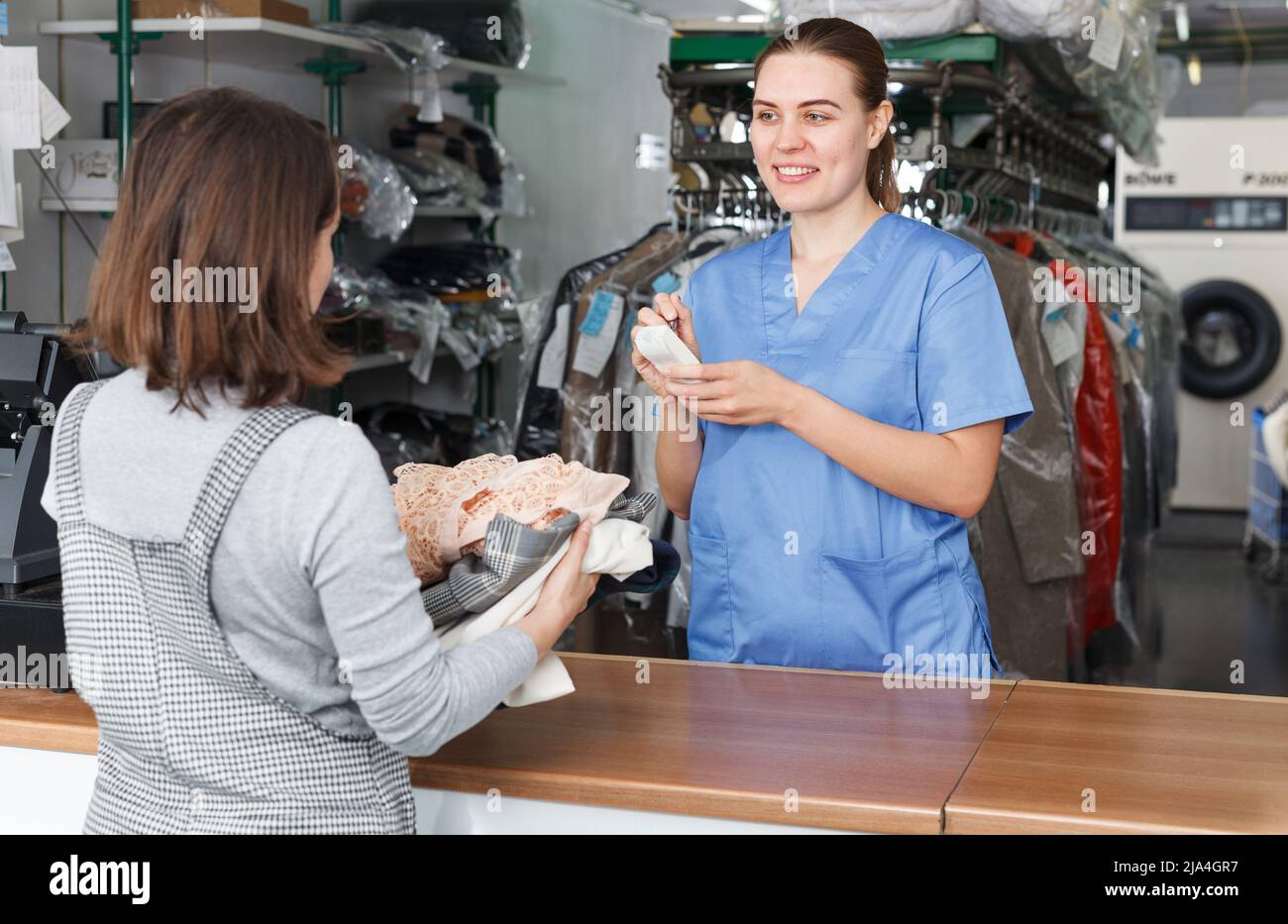Woman receiving clothing for dry cleaning Stock Photo - Alamy