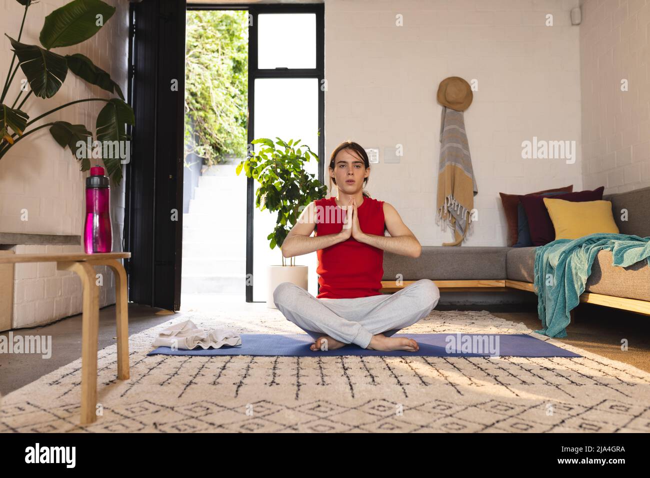 Non-binary trans woman practicing yoga and meditation sitting on yoga ...