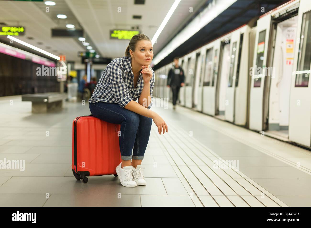 Woman sitting on suitcase at metro station Stock Photo - Alamy