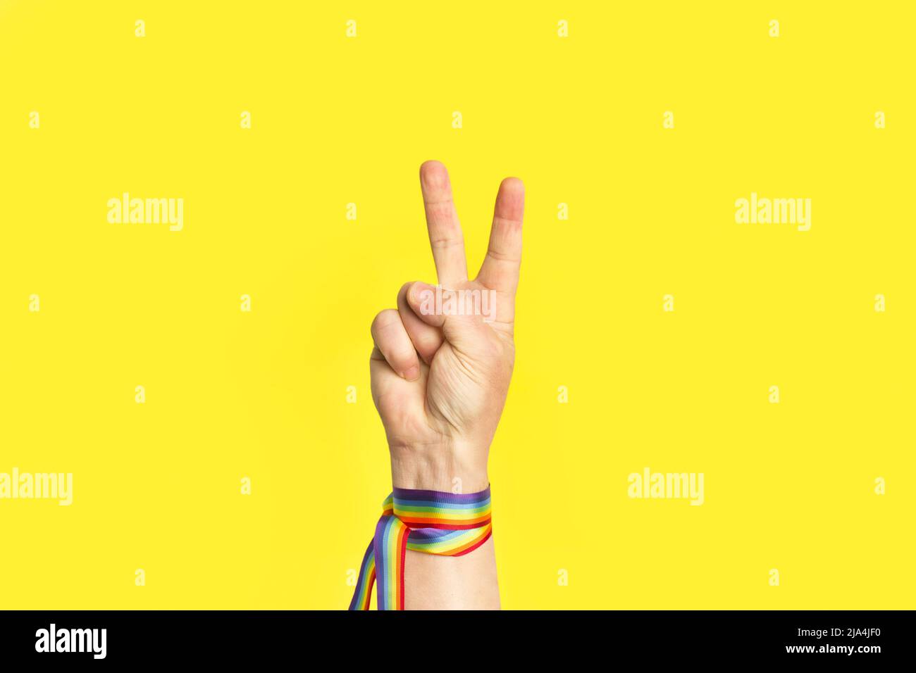 Man hand doing victory gesture with a rainbow ribbon in his wrist on a ...