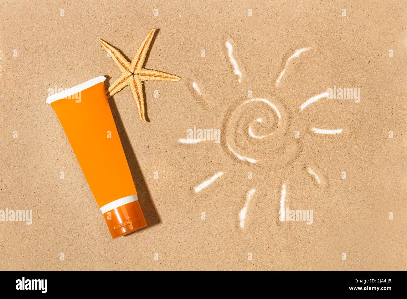 A sun tan lotion and a drawing of the sun on the sand in a top view ...