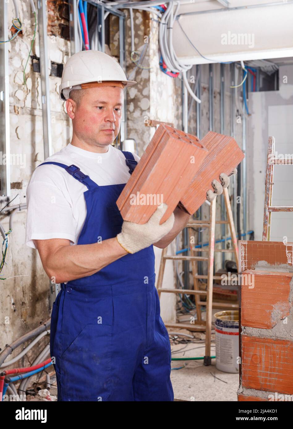 Bricklayer installing brick wall Stock Photo - Alamy