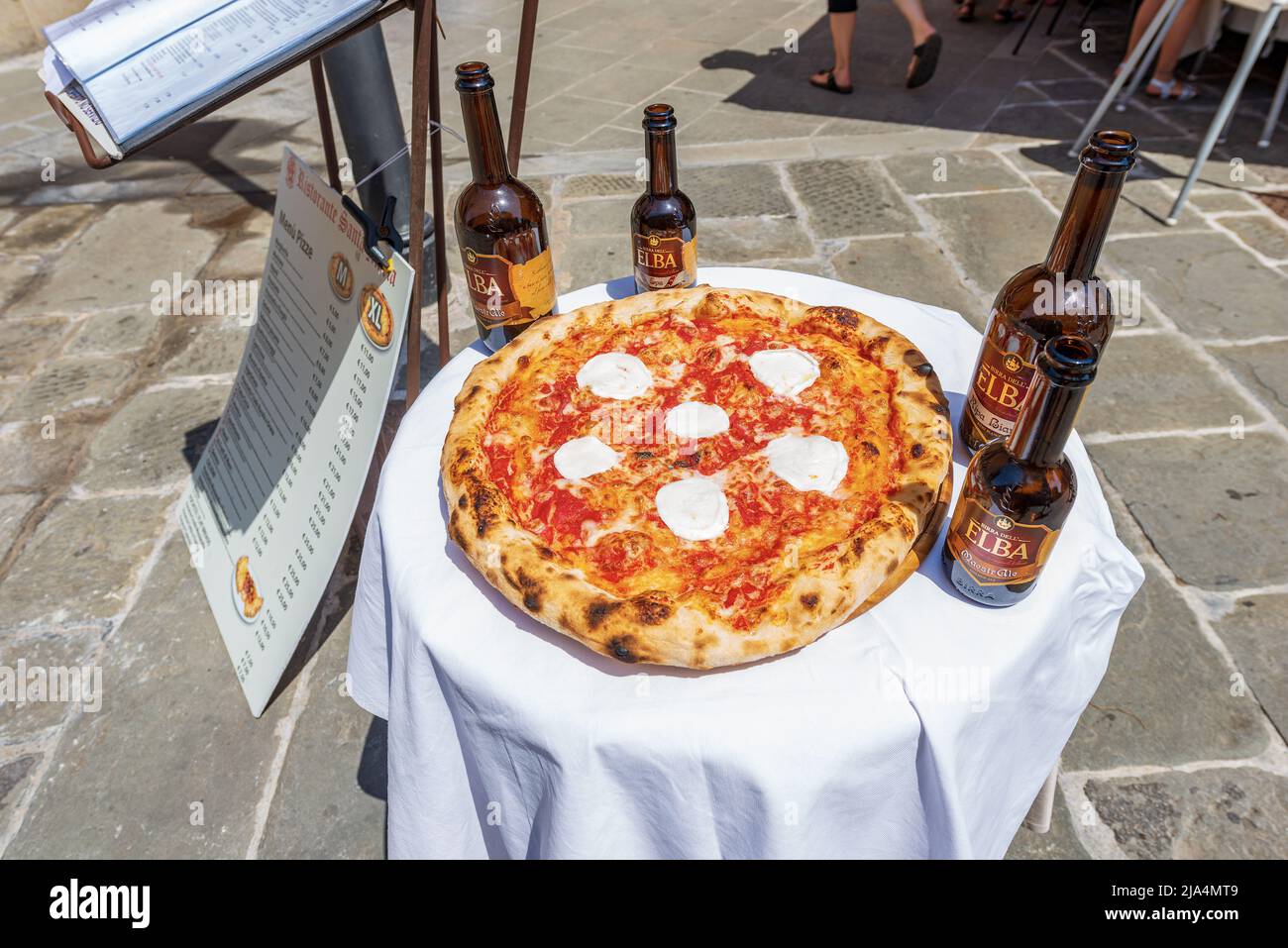 Margherita pizza, bottles of Elba beer on a table with and a menu in an ...