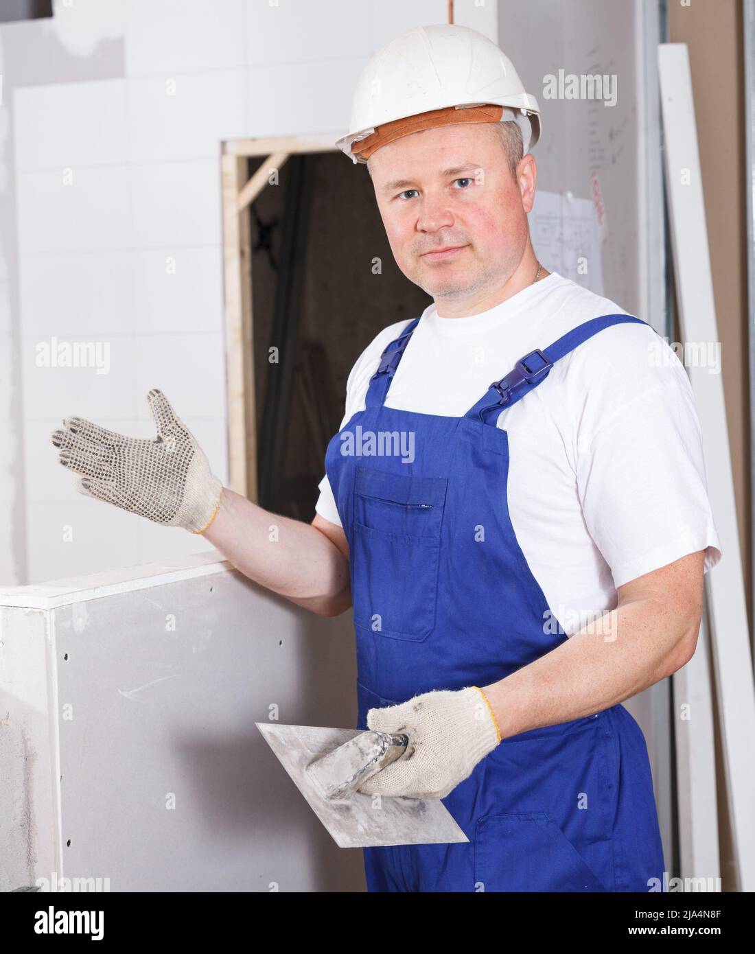 Builder filling gaps on drywall element Stock Photo - Alamy