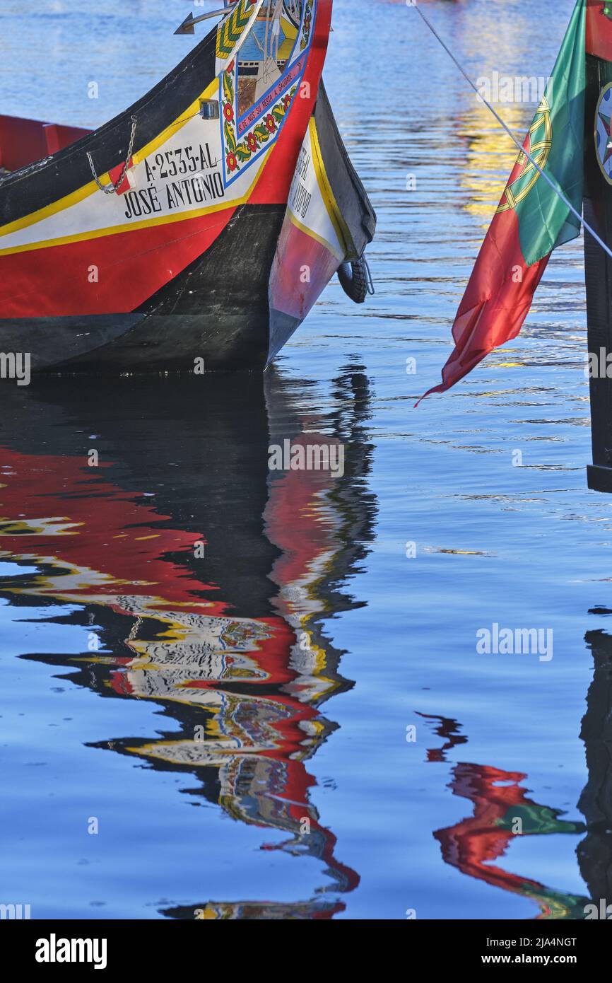 reflection and colorful Moliceiros boat moored along a canal in Aveiro ...