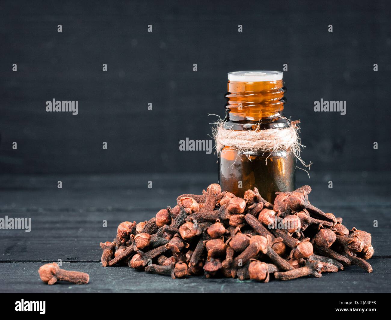Spice clove essential oil in dark glass bottle and dry cloves on dark ...