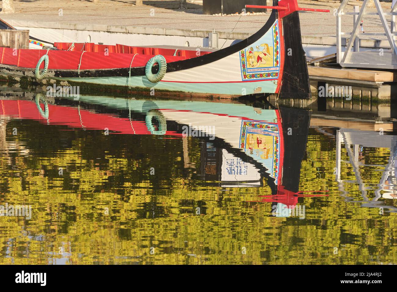 reflection and colorful Moliceiros boat moored along a canal in Aveiro ...