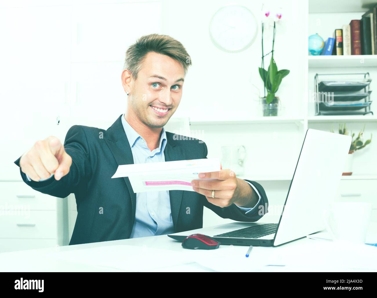Man sitting with laptop and having paper document Stock Photo - Alamy