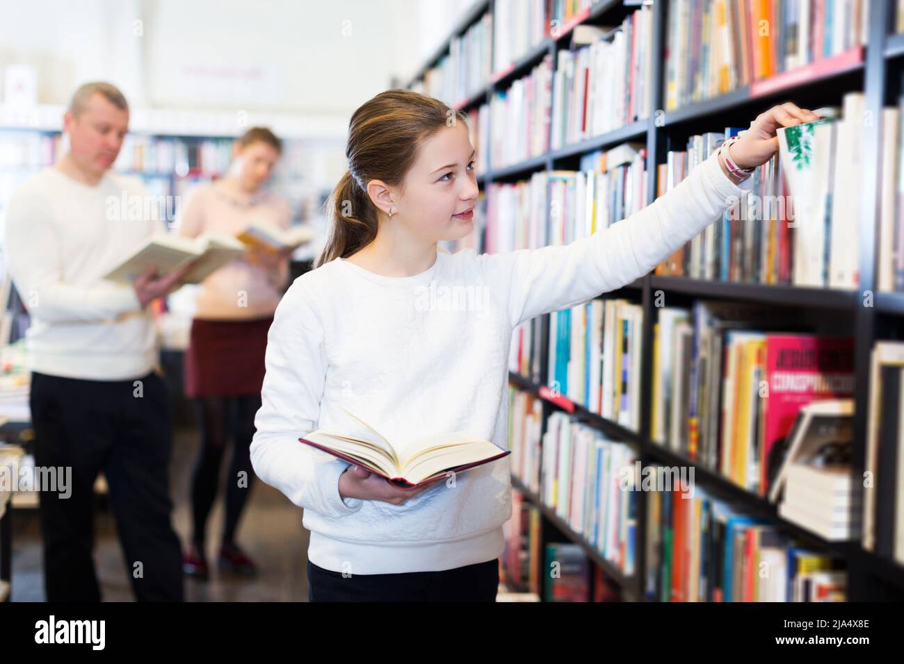girl searching for textbooks on bookshelves Stock Photo - Alamy