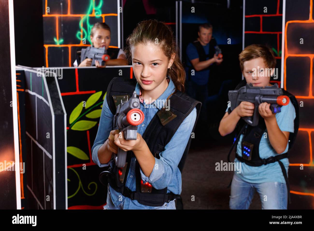 Portrait of teenager girl with laser gun having fun with her family on ...