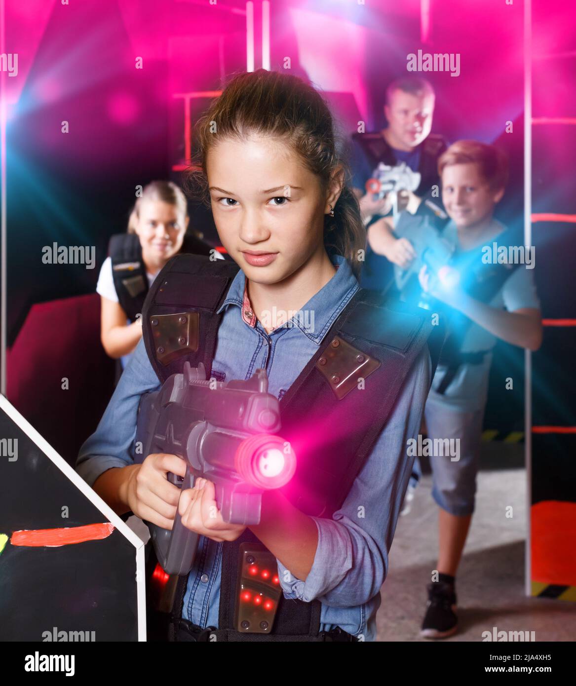 Girl aiming laser gun at other players Stock Photo - Alamy