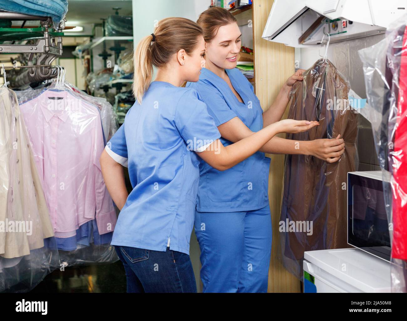 Two young women working in modern dry cleaner Stock Photo - Alamy