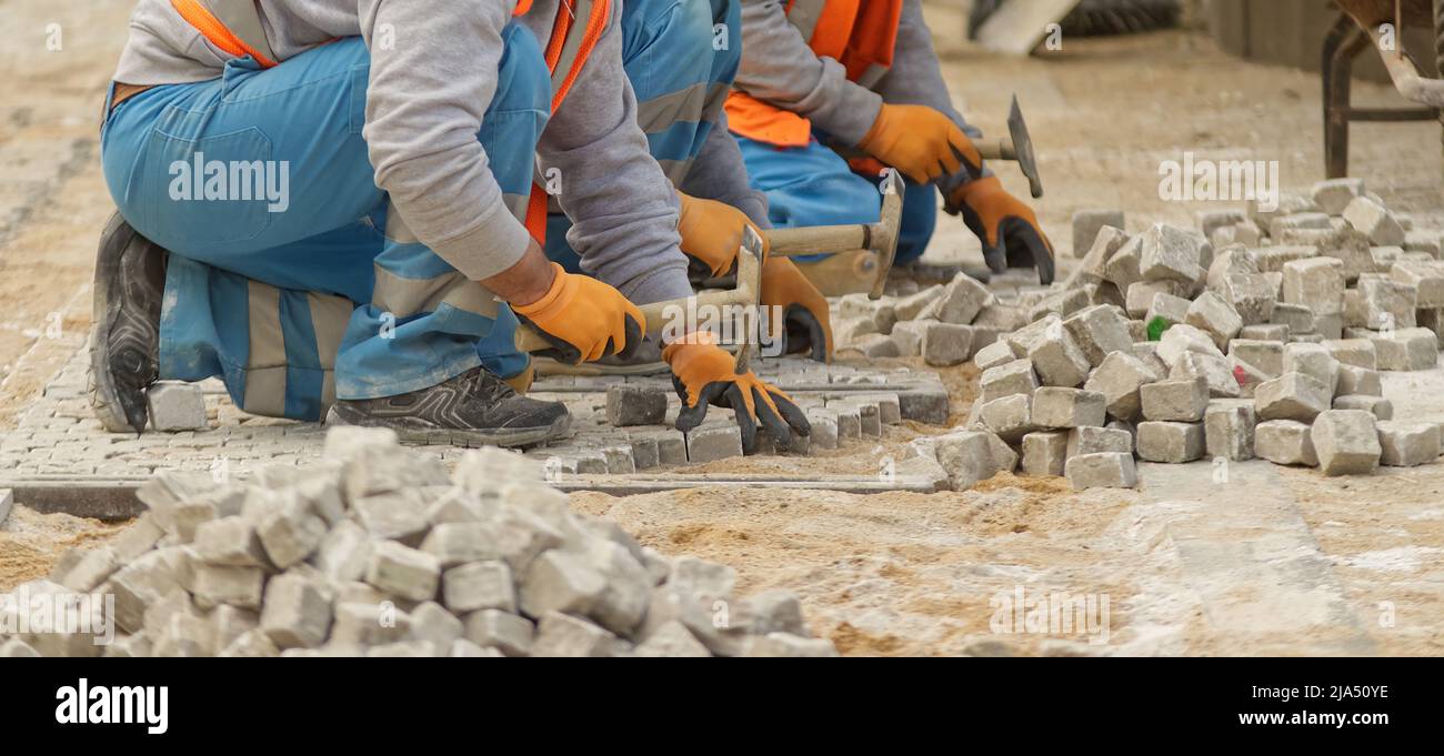 Pavers laying paving stones and creating a new sidewalk in the city ...