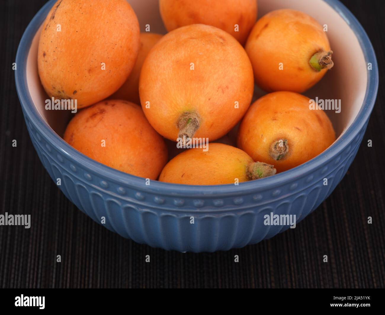 Loquat fruits in a blue bowl. Low key. Close up Stock Photo - Alamy