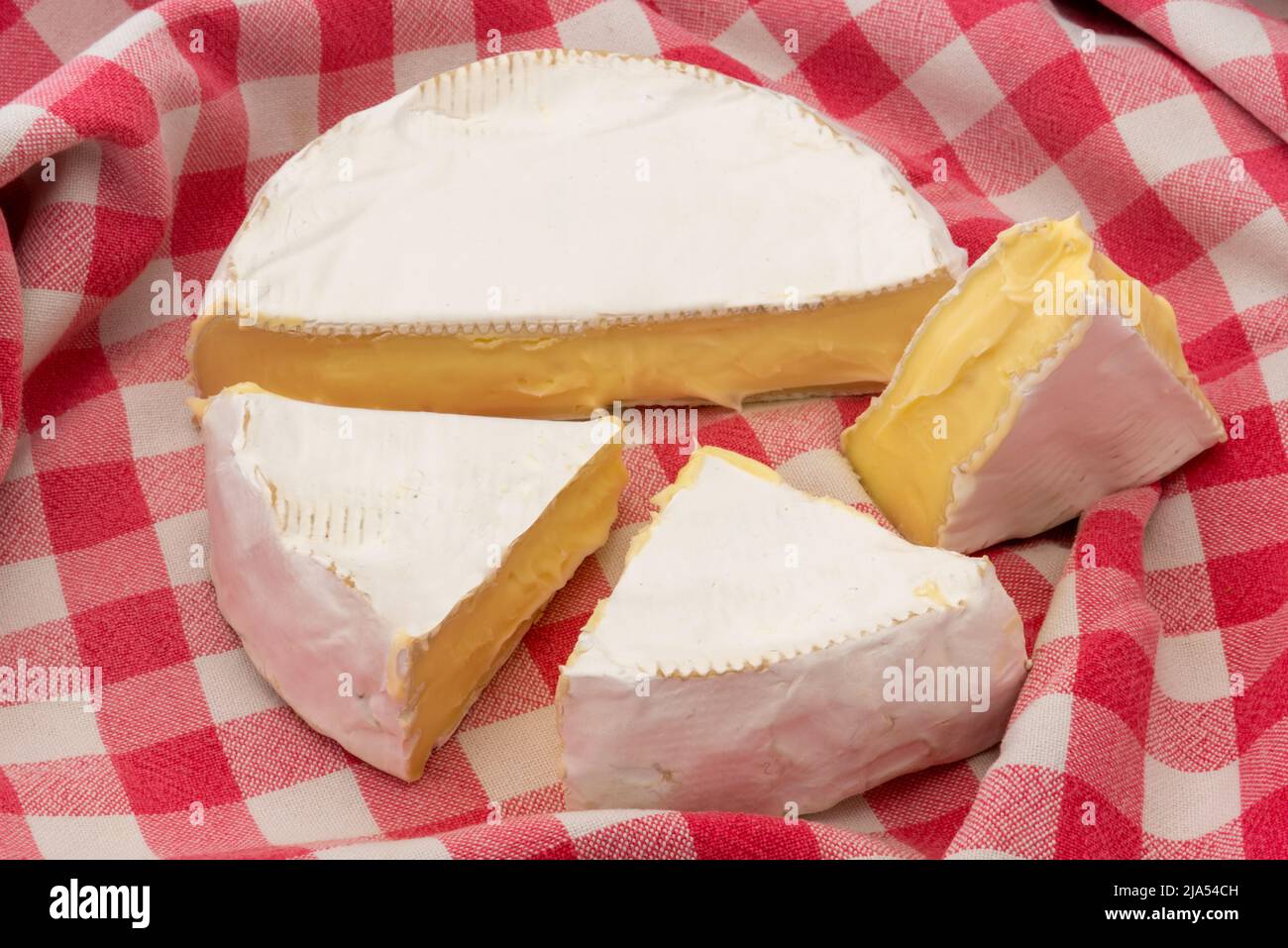 Wheel of Brie Cream Cheese cut with slices on a red checkered ...