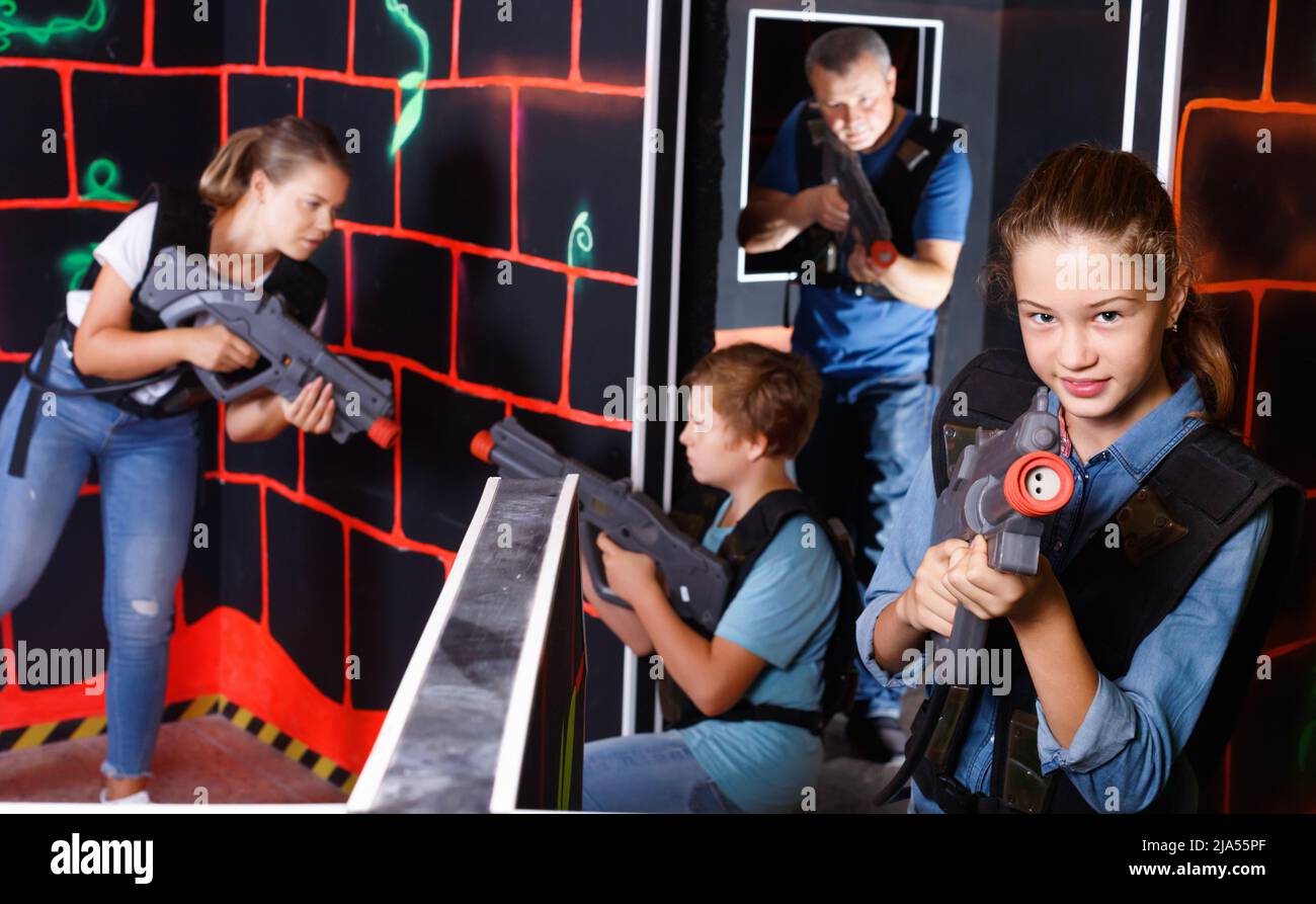 Portrait of teenager girl with laser gun having fun with her family on ...