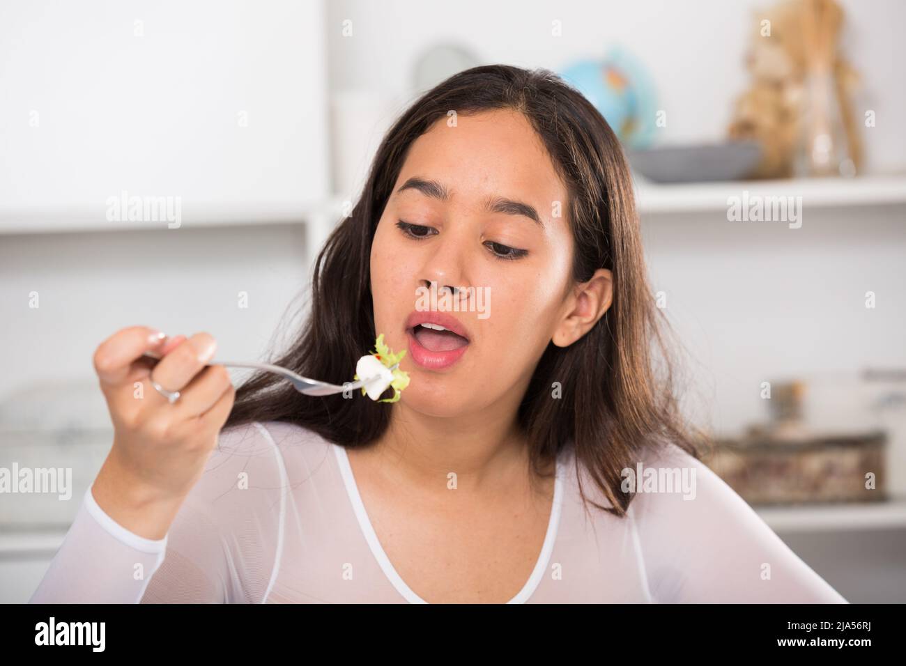 Positive young female eating salad Stock Photo - Alamy