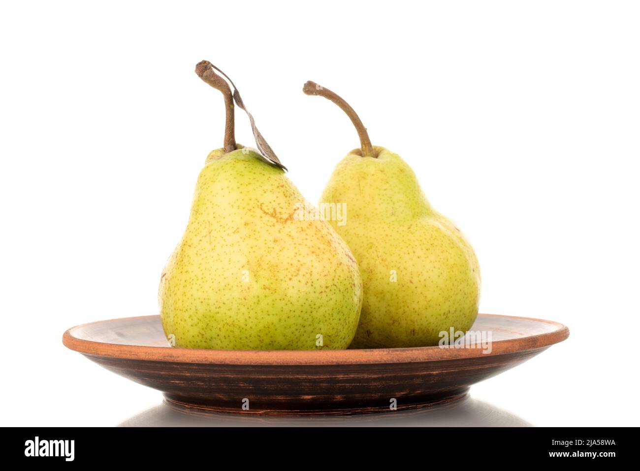 Two juicy bright yellow pears on a clay plate, close-up, isolated on a ...