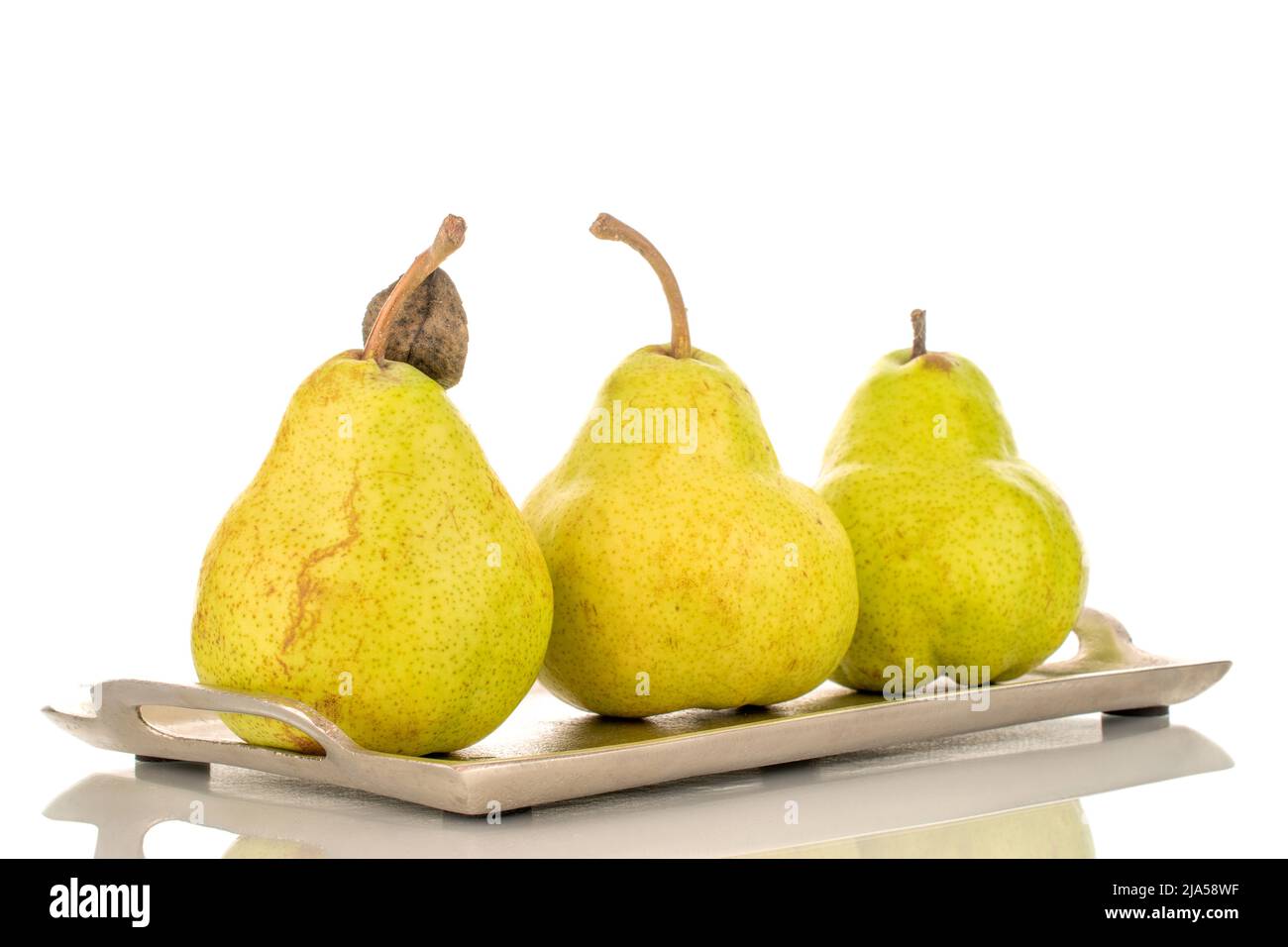 Three juicy bright yellow pears on a metal tray, close-up, isolated on ...