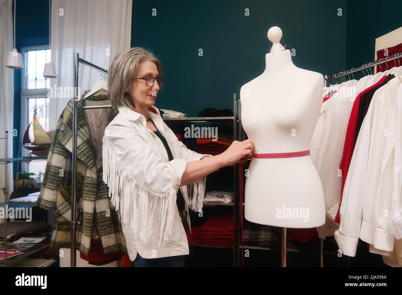 Stylish elegant European elderly woman fashion designer using measure ...