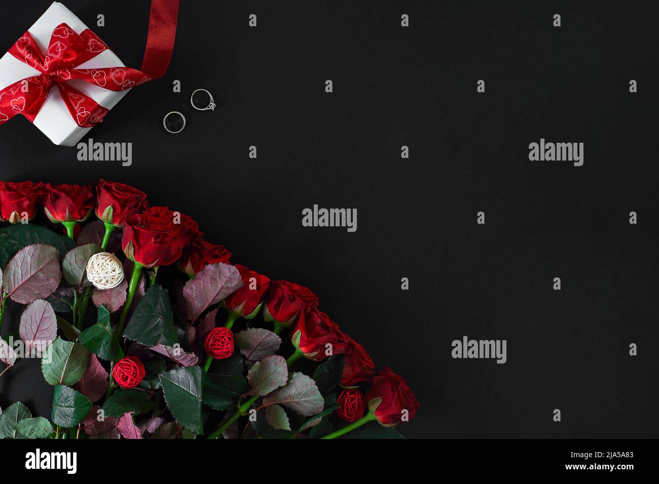 Red roses, ring and gift box on black background Stock Photo - Alamy