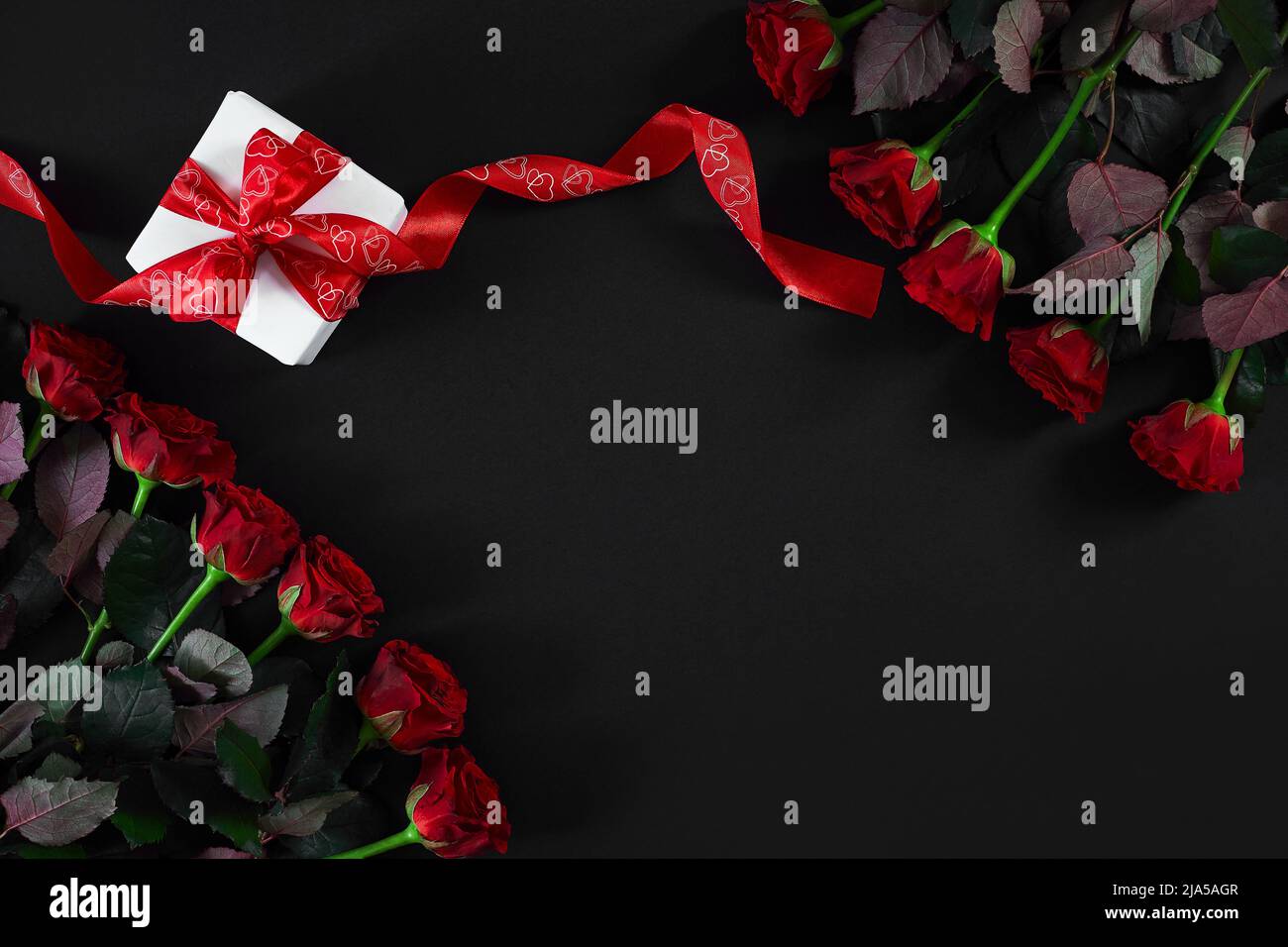 Red roses, ring and gift box on black background Stock Photo - Alamy