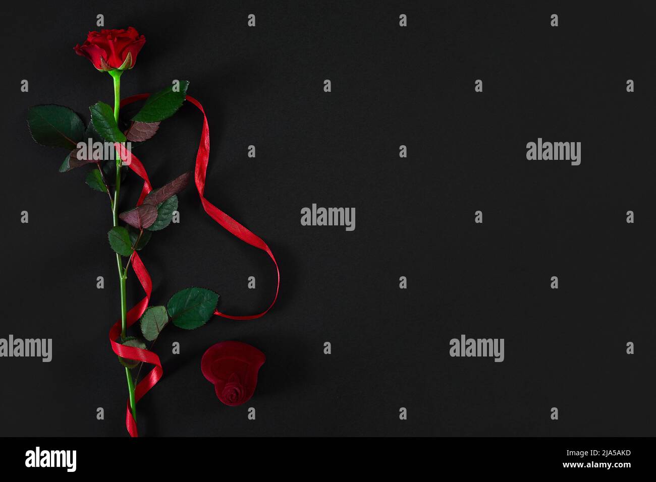 One dark red rose with red ribbon and box with ring on black bac Stock ...