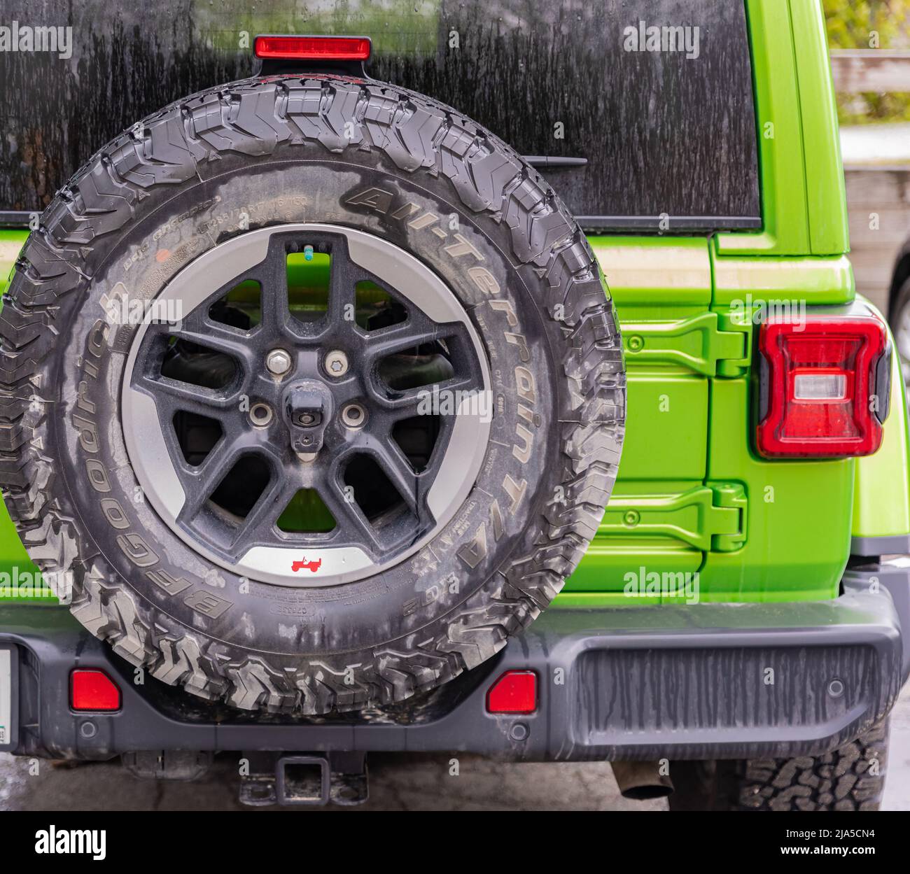 Jeep vehicle on an outdoor parking lot on a rainy day, back view. Spare ...