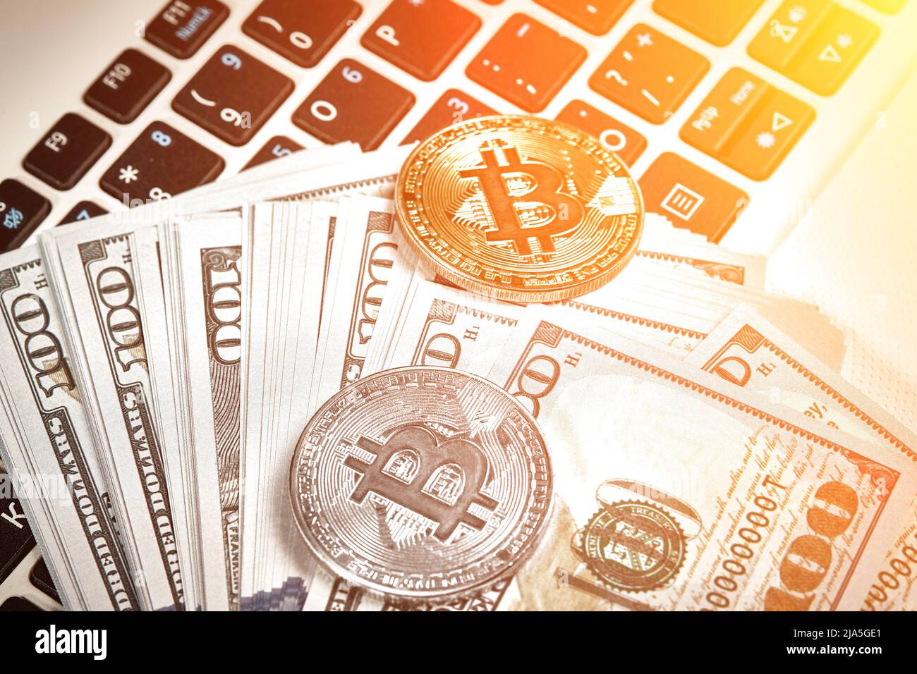 Bitcoins with dollar bills on laptop keyboard. Sun flare Stock Photo ...