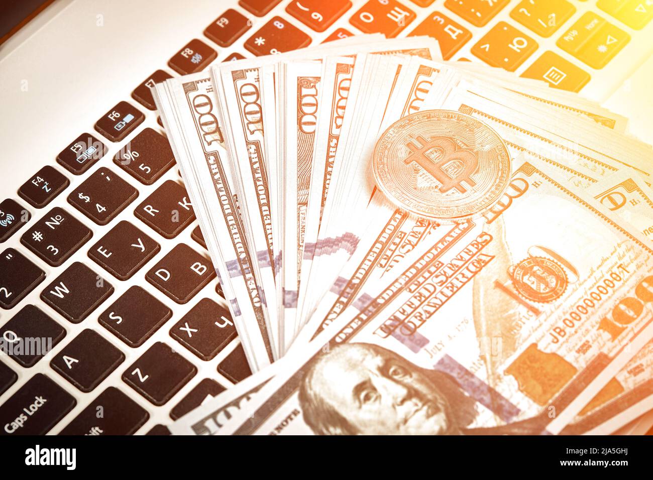 Bitcoins with dollar bills on laptop keyboard. Sun flare Stock Photo ...
