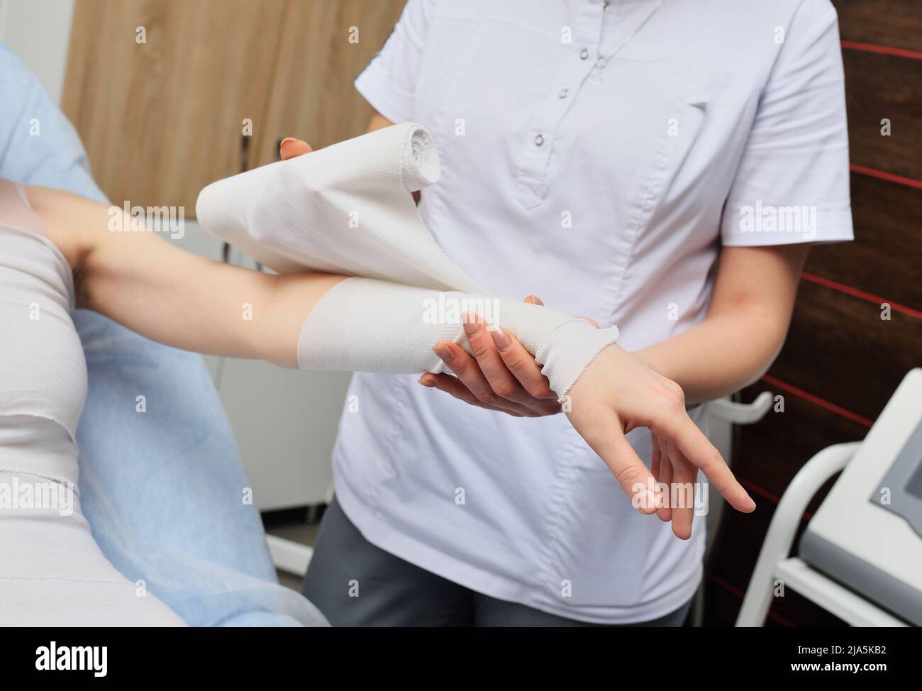 beautician wraps the patient's leg - a young pretty woman with bandages ...