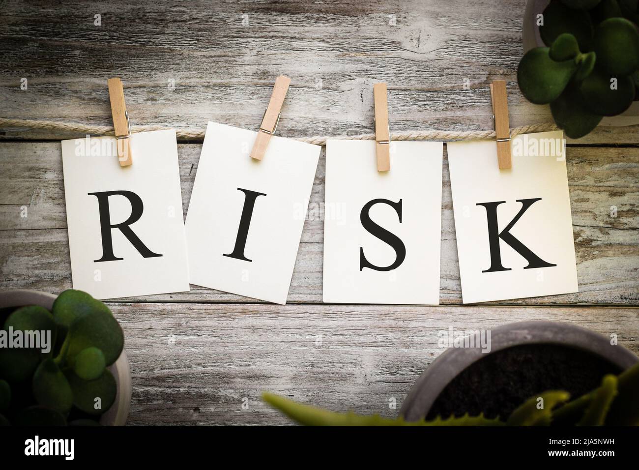 A set of printed cards spelling the word RISK on an aged wooden ...